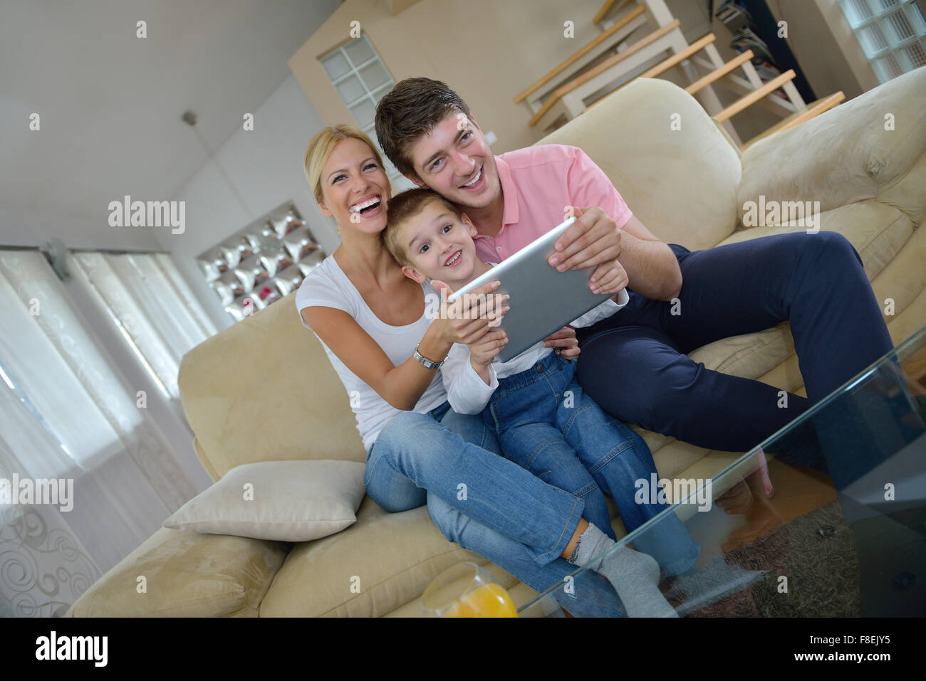 happy young family using tablet computer at modern home for playing ...