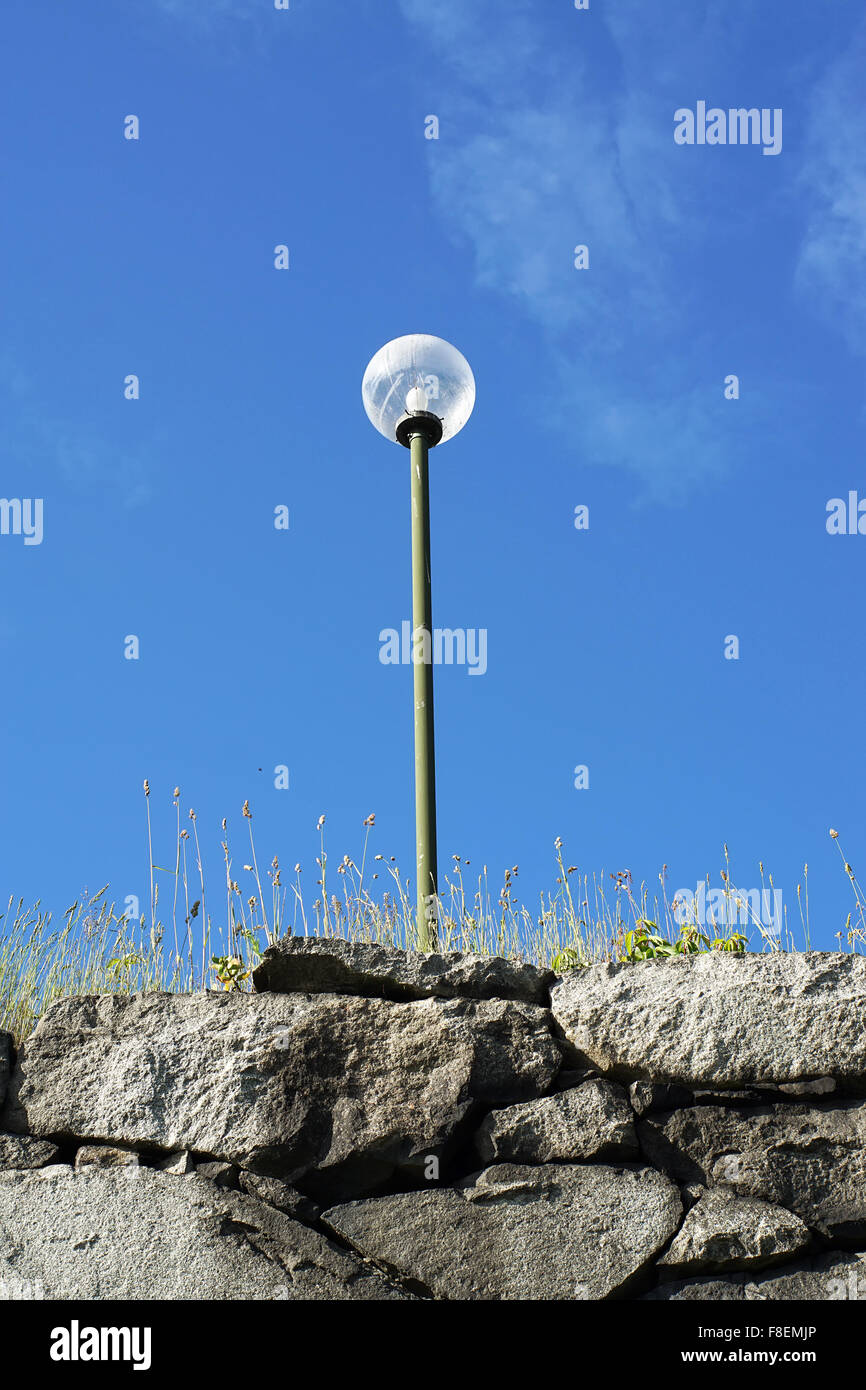 Street bubble lamp post on grassy stone wall against blue sky Stock ...