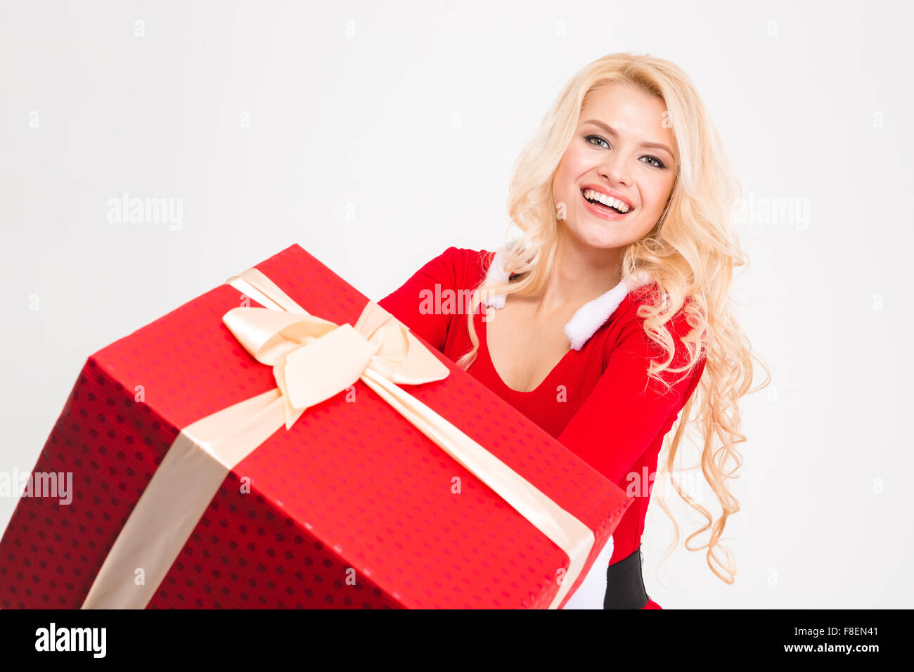 Cheerful joyful young female smiling and holding big red present box ...