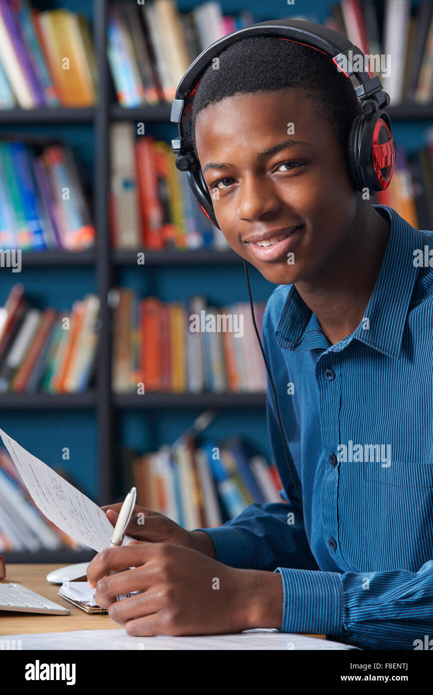 Male Teenage Student Working At Computer Wearing Headphones Stock Photo ...