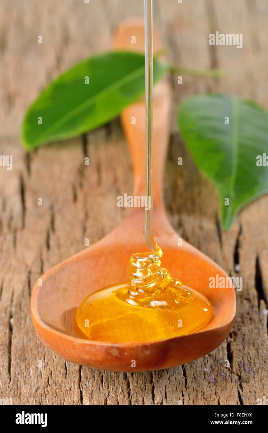 honey pouring into wooden spoon Stock Photo - Alamy