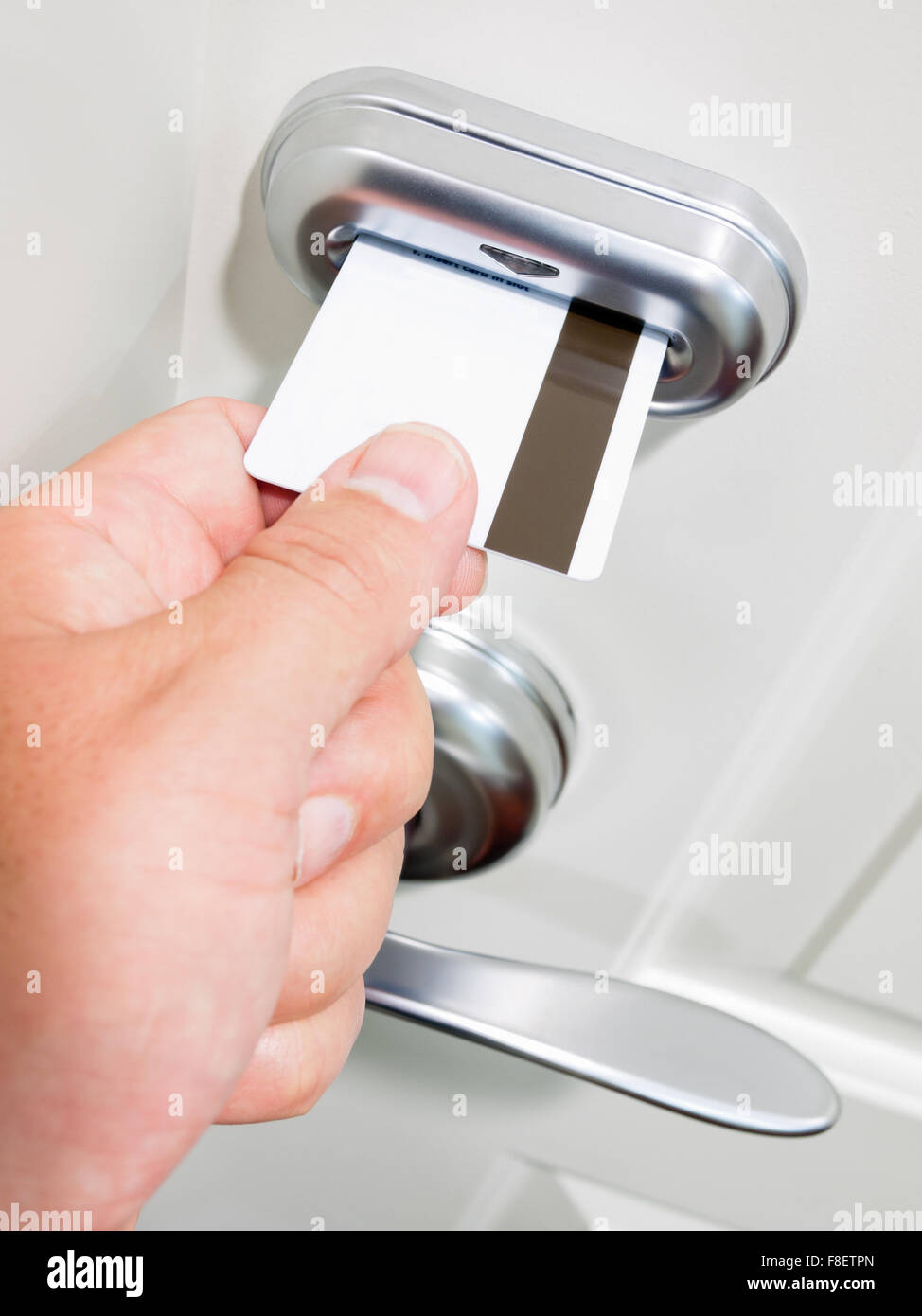 A person's hand sliding a card key into an electronic door lock ...