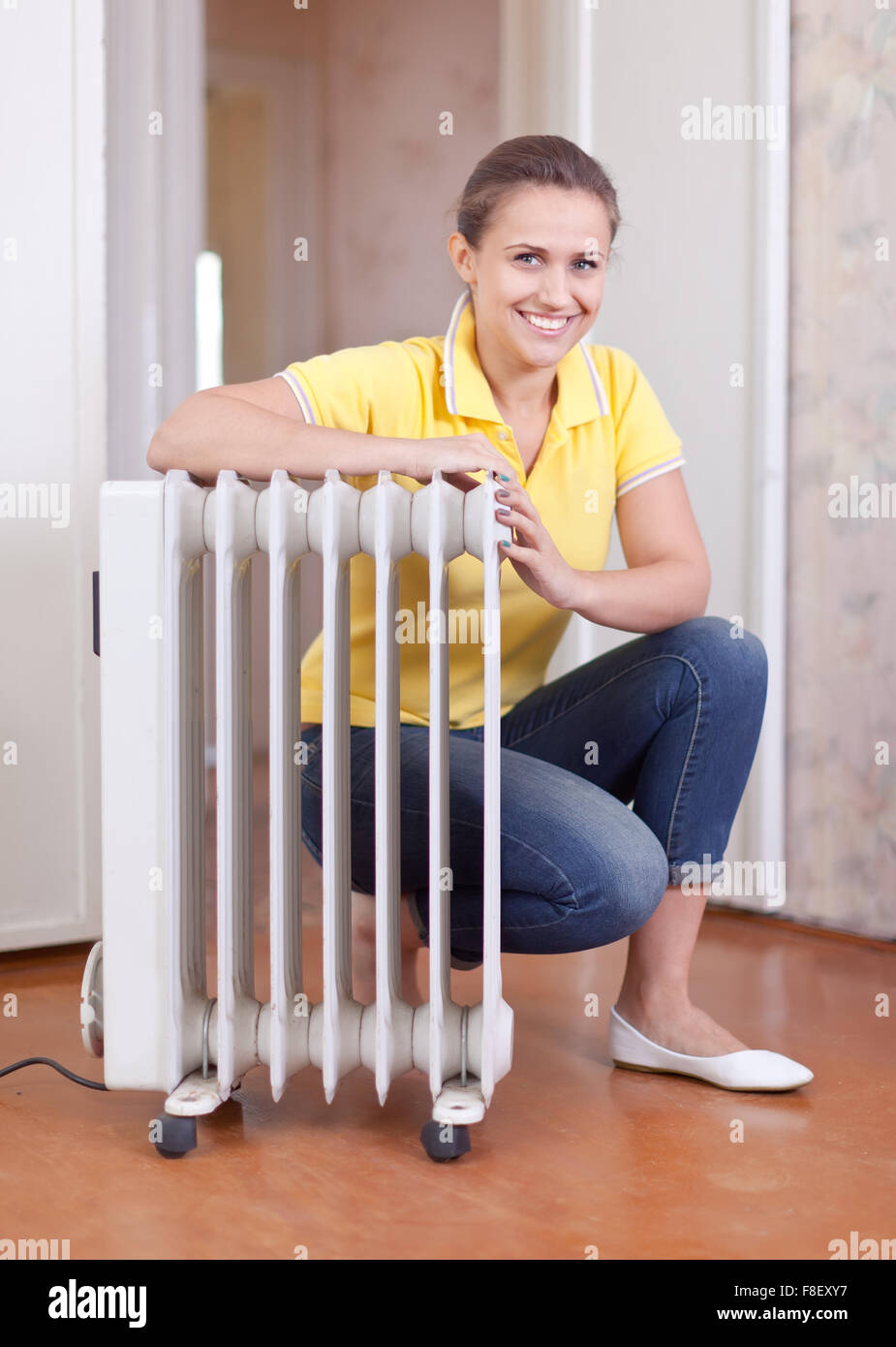 smiling woman near warm radiator in home Stock Photo - Alamy