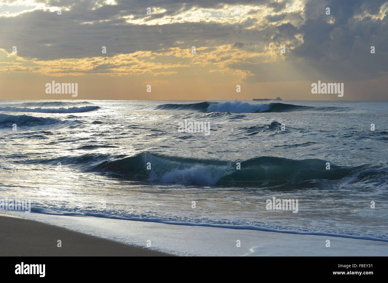 Sunrise through clouds with sea skyline Stock Photo - Alamy