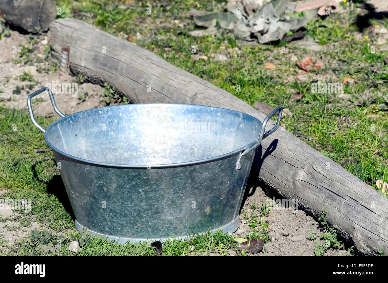 Metallic wash tub, over garden grass, beside of a trunk Stock Photo - Alamy