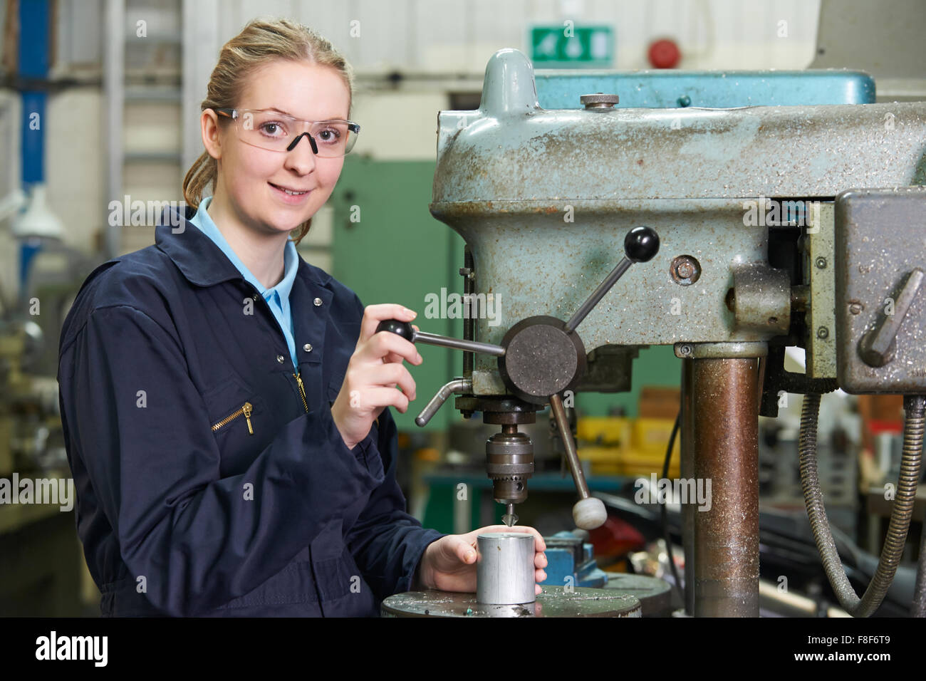 Female Apprentice Engineer Using Drill In Factory Stock Photo - Alamy