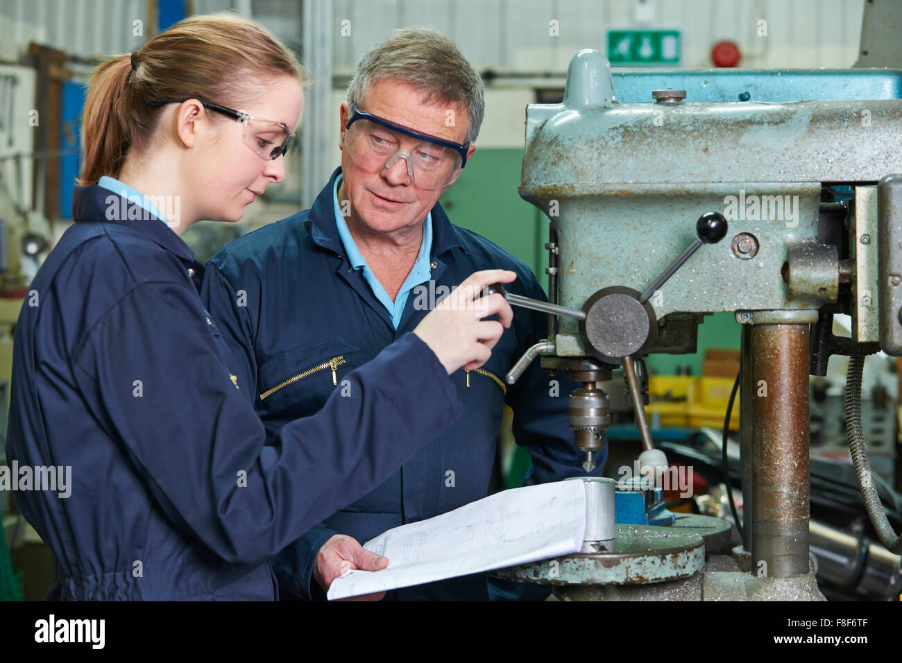 Engineer Showing Female Apprentice How To Use Drill In Factory Stock ...