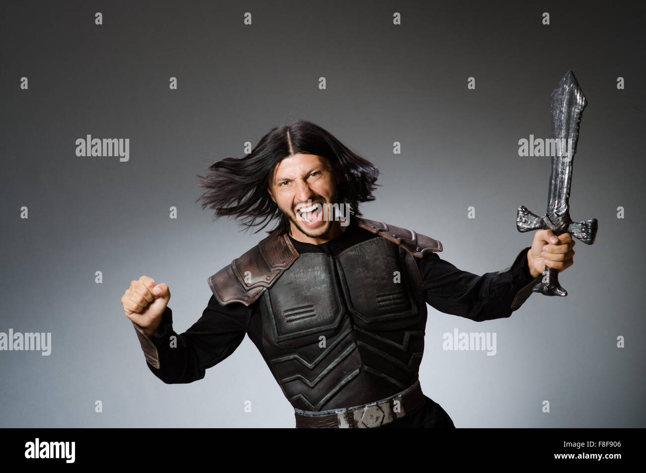 Angry knight with sword against dark background Stock Photo - Alamy