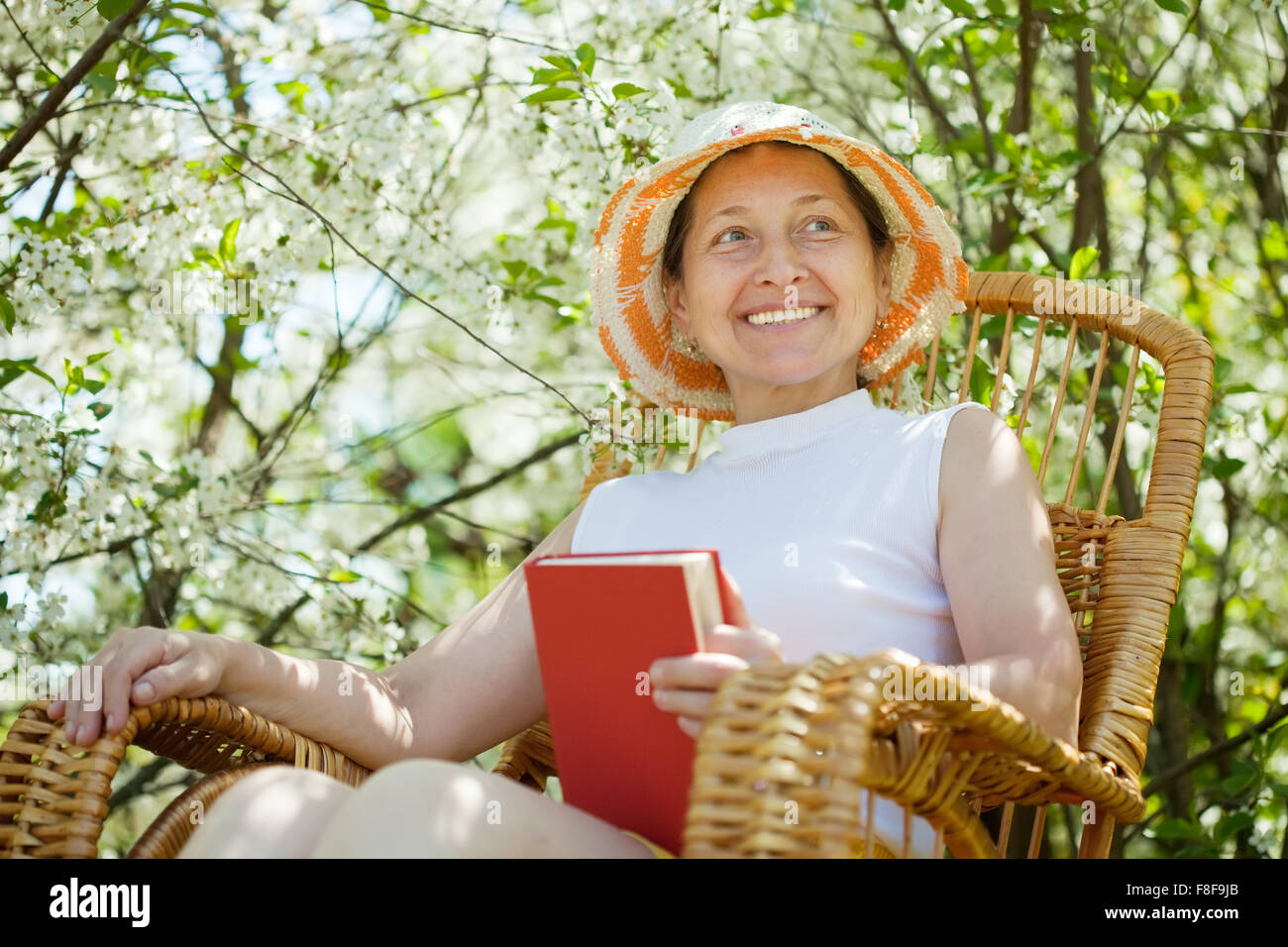 Relaxing mature woman in rocking-chair against bloom garden Stock Photo ...
