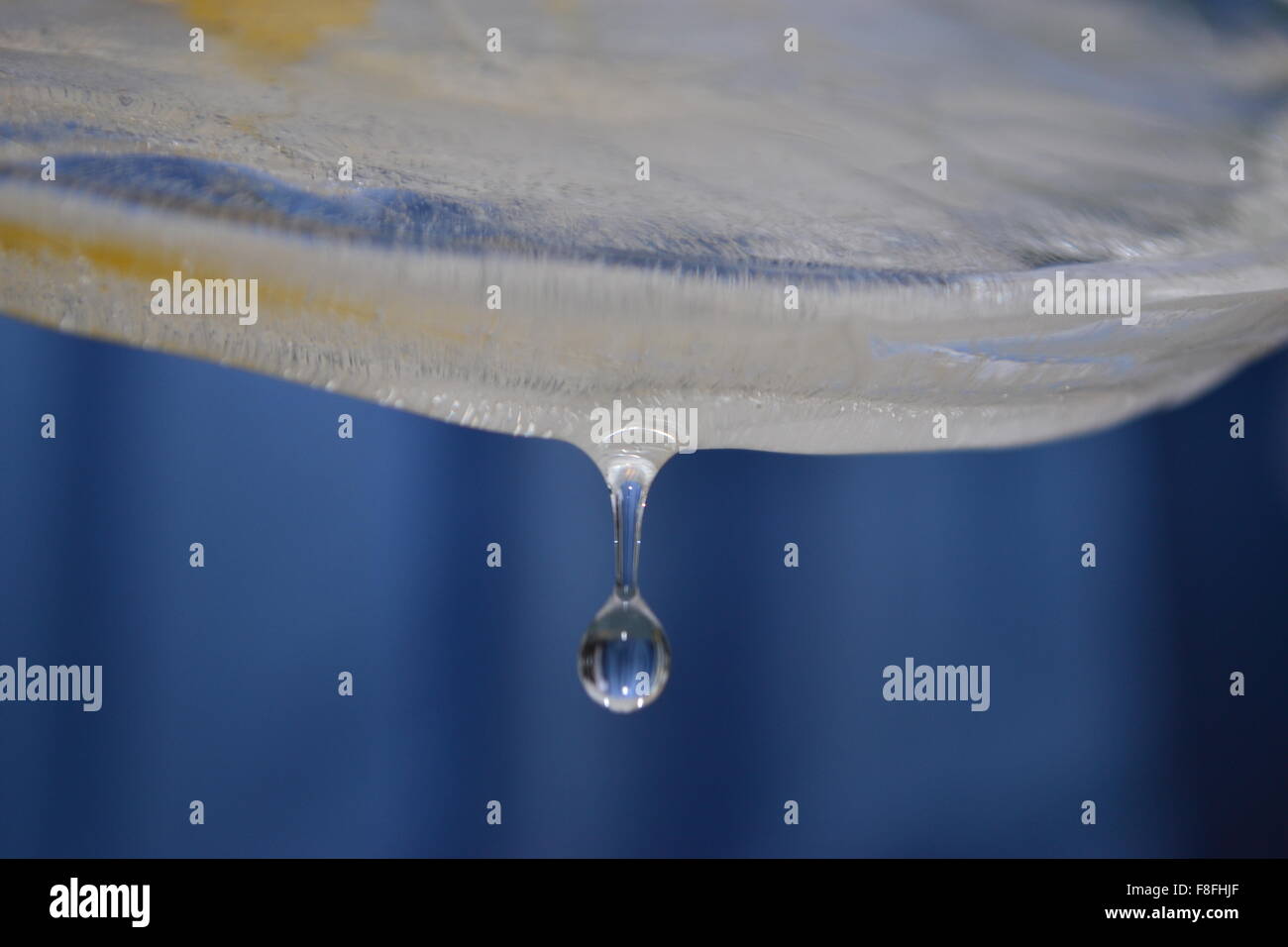 Water drop dripping from ice on blue background Stock Photo - Alamy