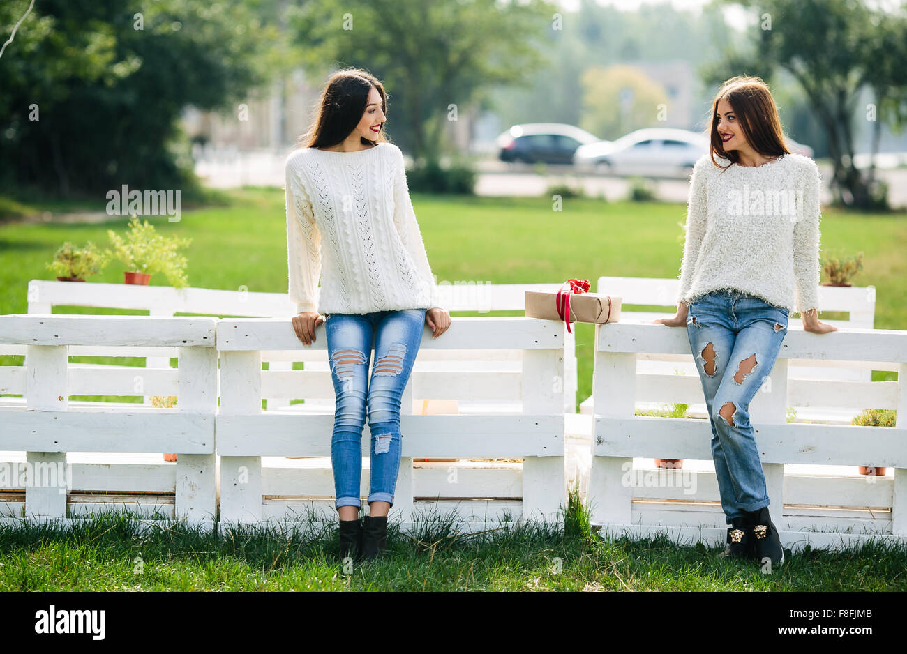 Two girls lean bench Stock Photo - Alamy