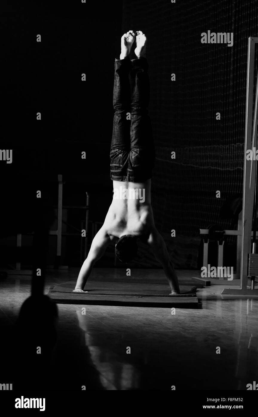 Young man performing handstand in fitness studio. rear, back ...