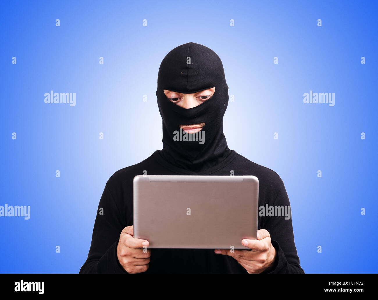 Hacker with computer wearing balaclava Stock Photo - Alamy