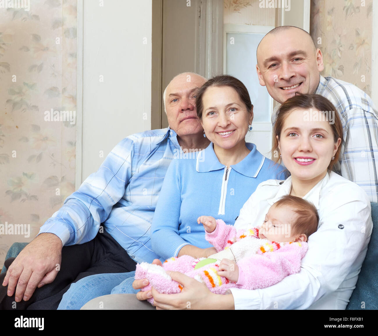 Portrait of happy three generations family with newborn baby at home ...