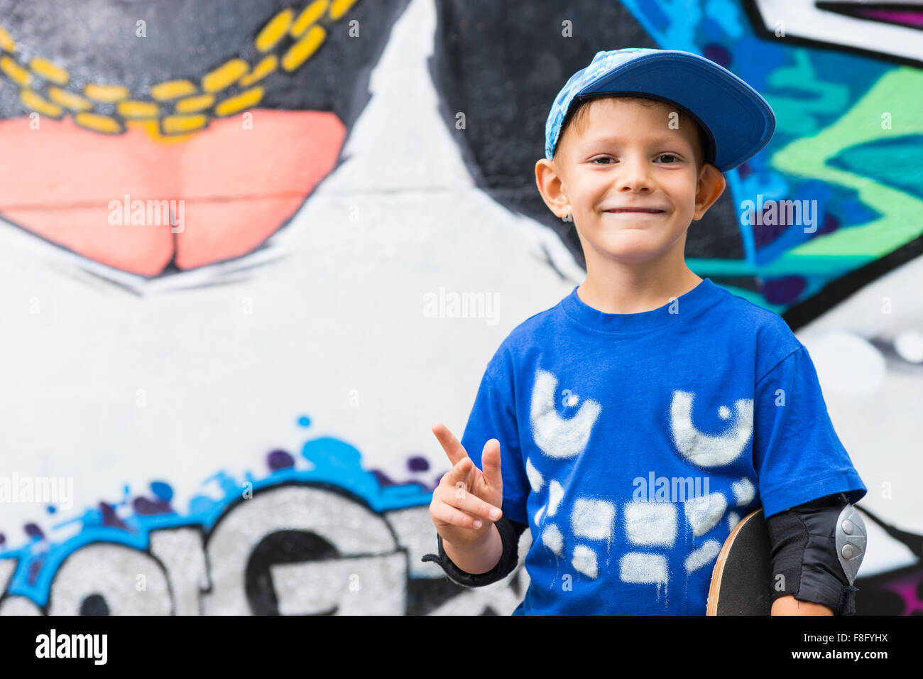 Funny playful kid wearing blue cap and T-shirt with a mean face printed ...