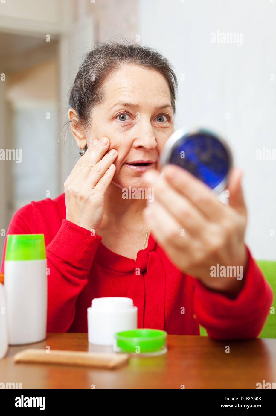 mature woman stares on facial rhytid in mirror at home Stock Photo - Alamy