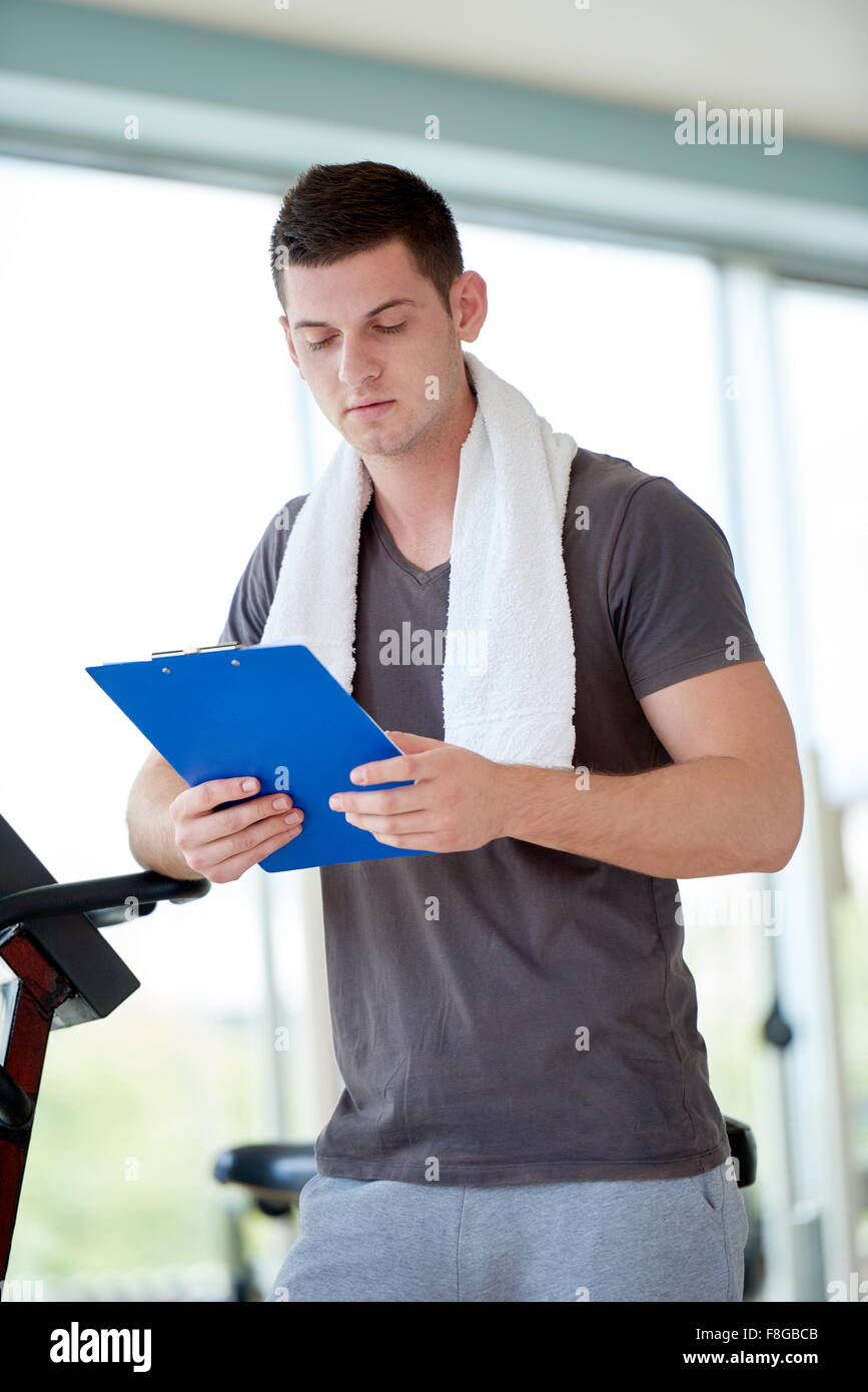 Portrait of a smiling male trainer with clipboard standing in a bright ...