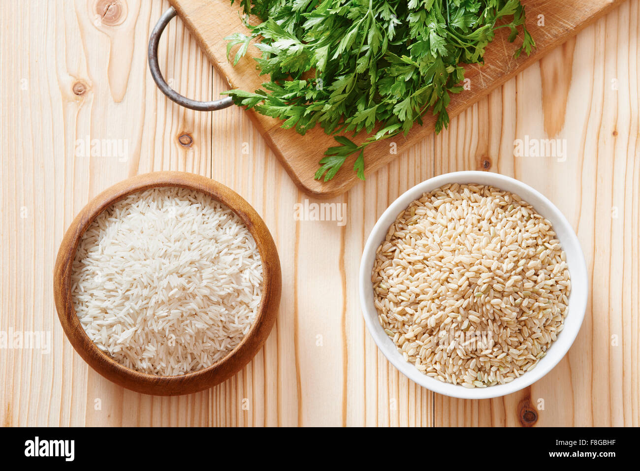 Basmati rice in bowl on light wooden table surrounded by ingredients ...
