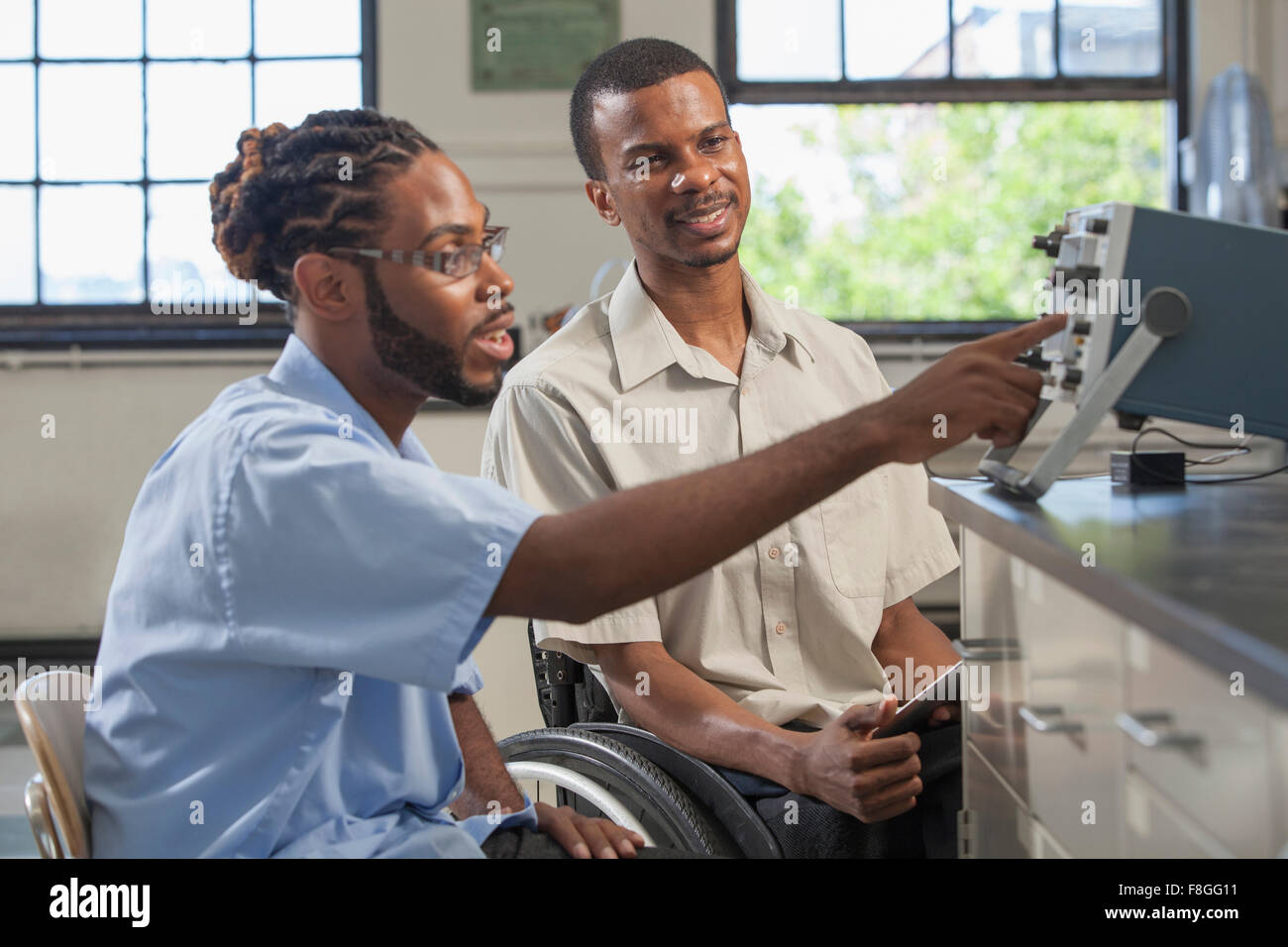 Paraplegic student and classmate working in science classroom Stock ...