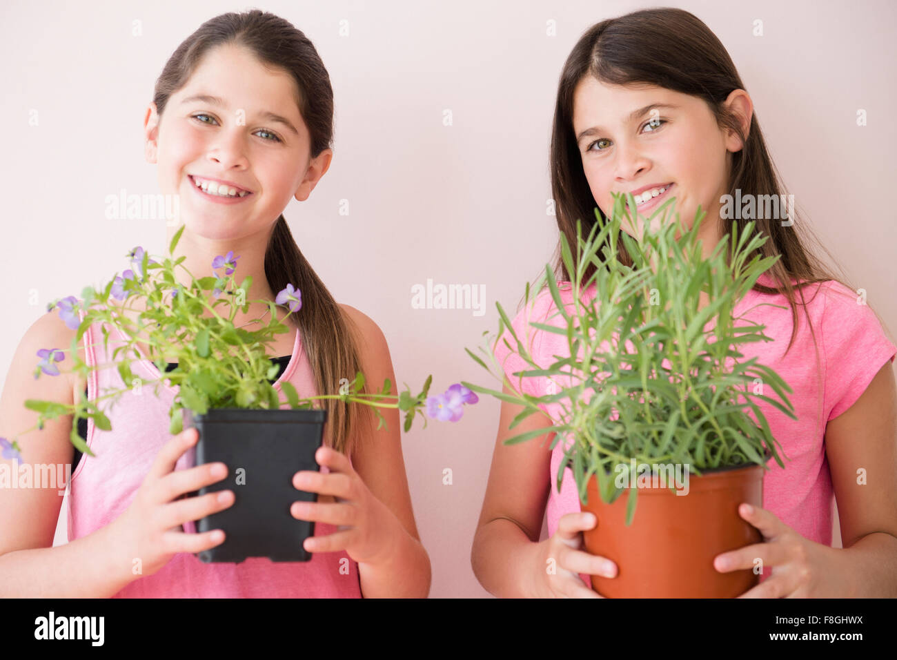 Caucasian twin sisters holding potted plants Stock Photo - Alamy