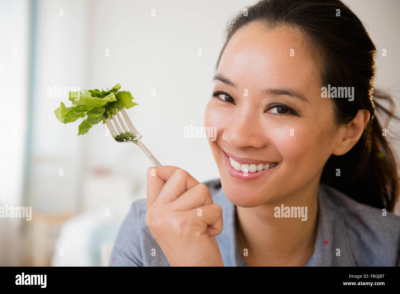 Chinese woman eating salad Stock Photo - Alamy