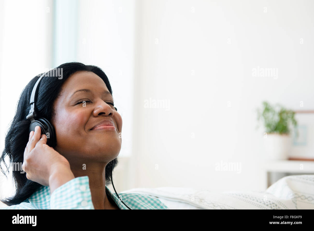 Black woman listening to headphones on sofa Stock Photo - Alamy