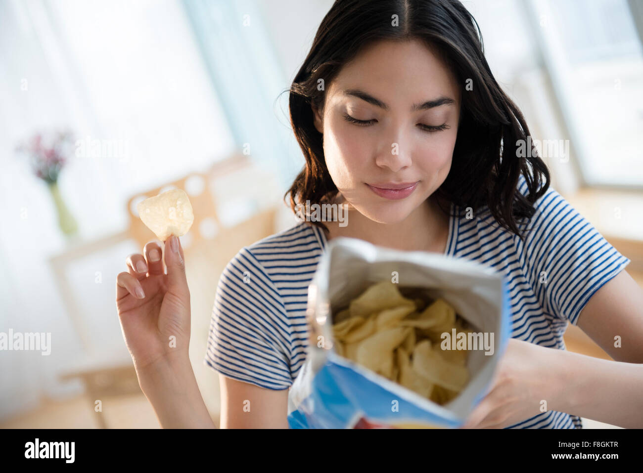 Hispanic woman reading ingredients on bag of potato chips Stock Photo ...