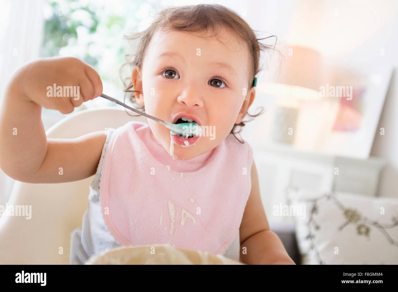 Mixed race baby girl eating yogurt Stock Photo - Alamy