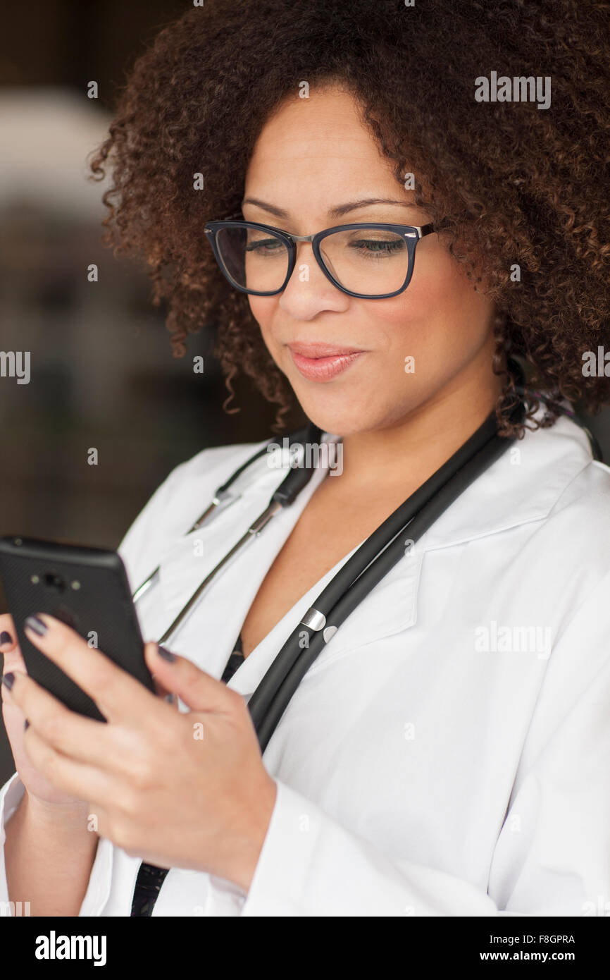 Mixed race doctor using cell phone Stock Photo - Alamy