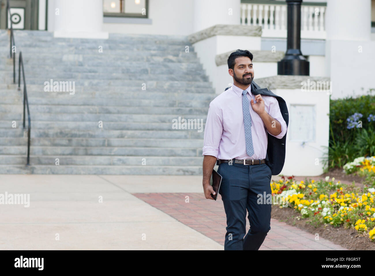 Indian businessman carrying digital tablet on sidewalk Stock Photo - Alamy