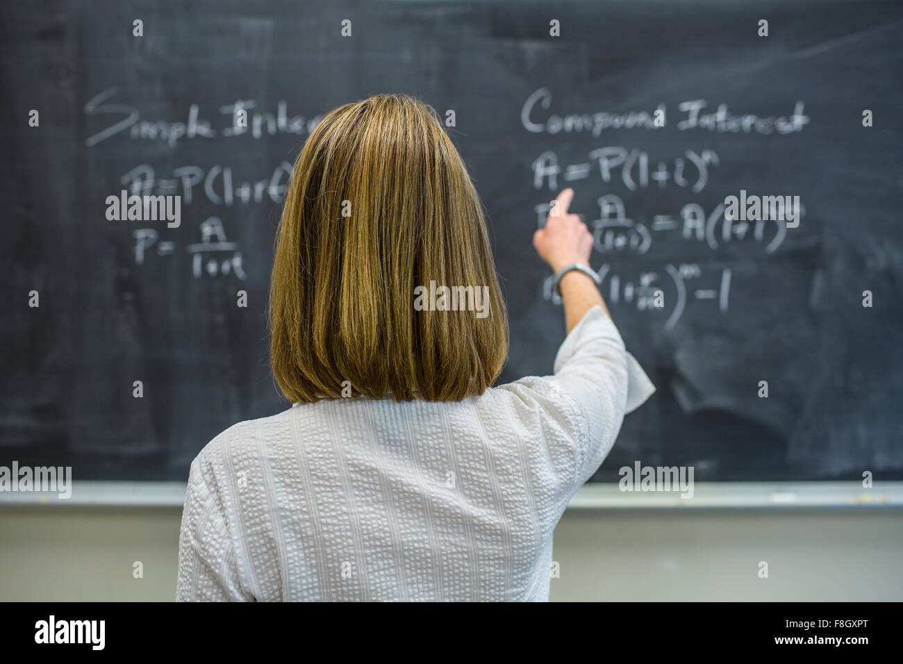 Caucasian teacher pointing to chalkboard Stock Photo - Alamy