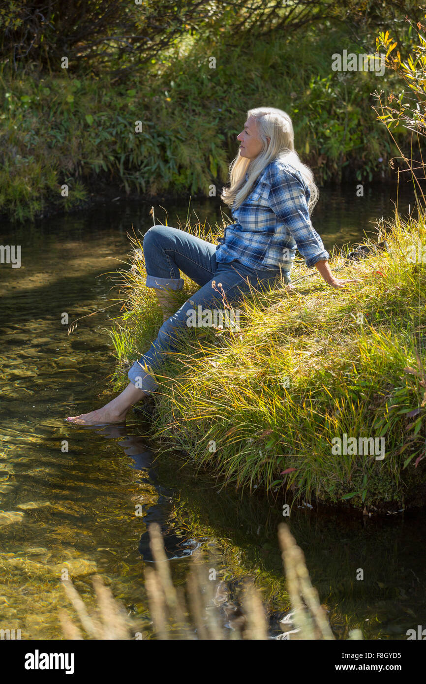 Caucasian woman dipping feet in river Stock Photo - Alamy