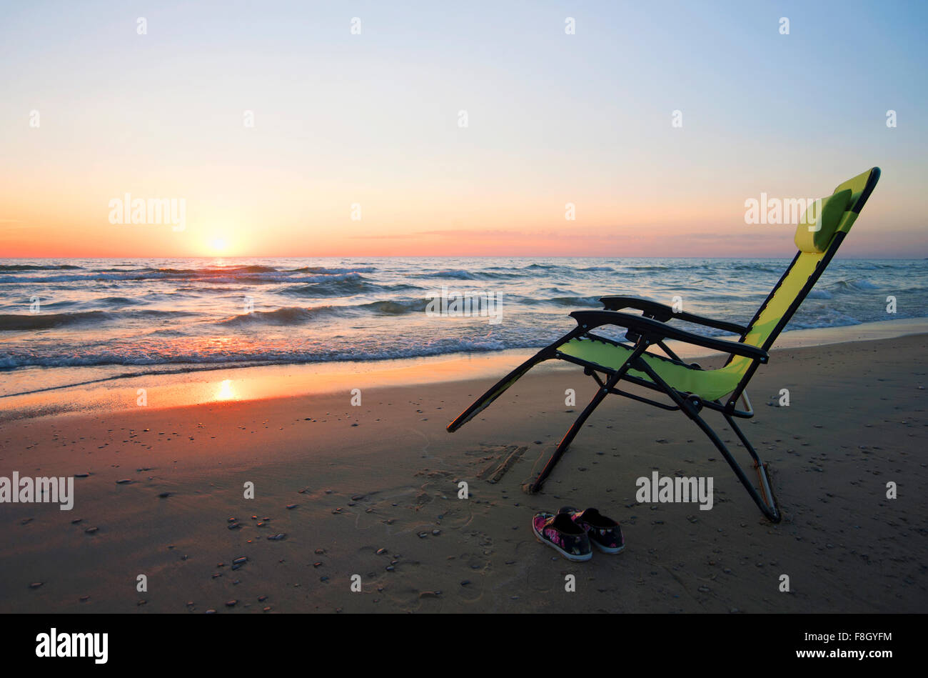 Lounge chair on beach at sunset Stock Photo - Alamy