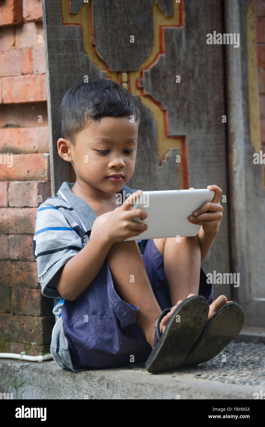 Asian boy using cell phone on front step Stock Photo - Alamy