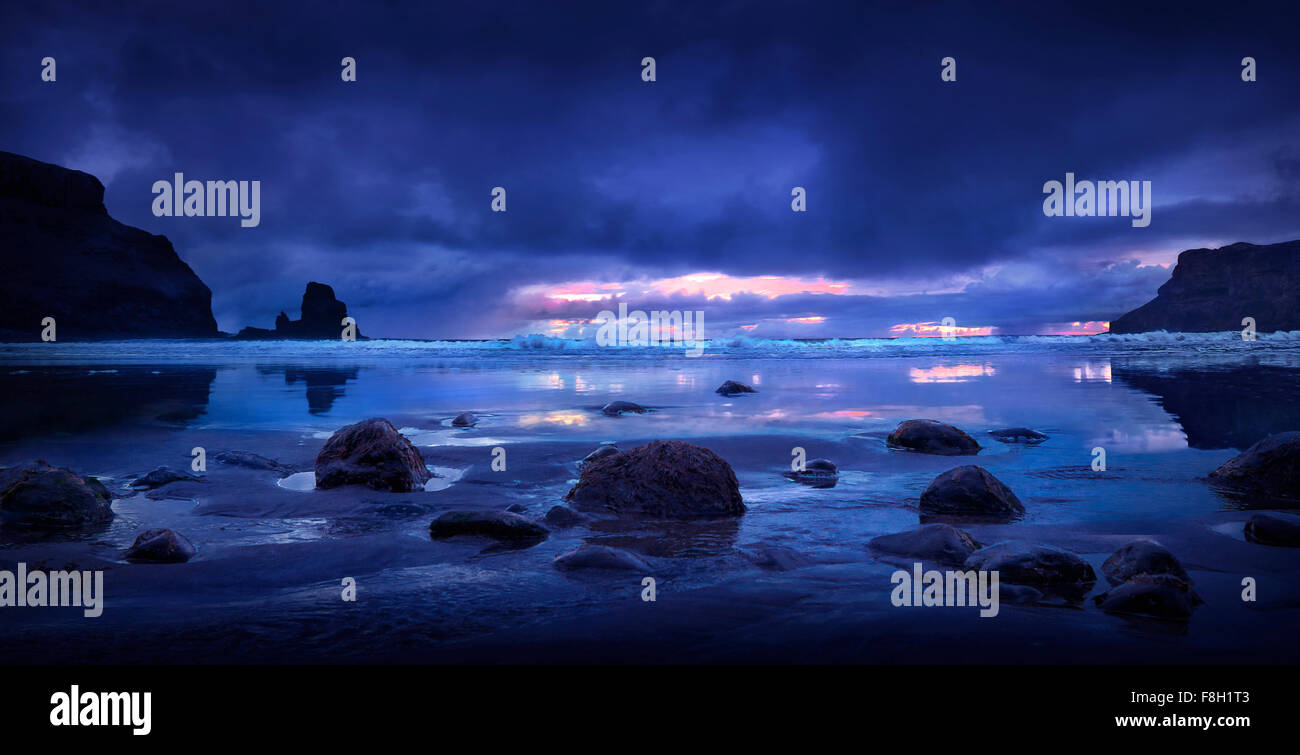 Rocks on beach under storm clouds Stock Photo - Alamy