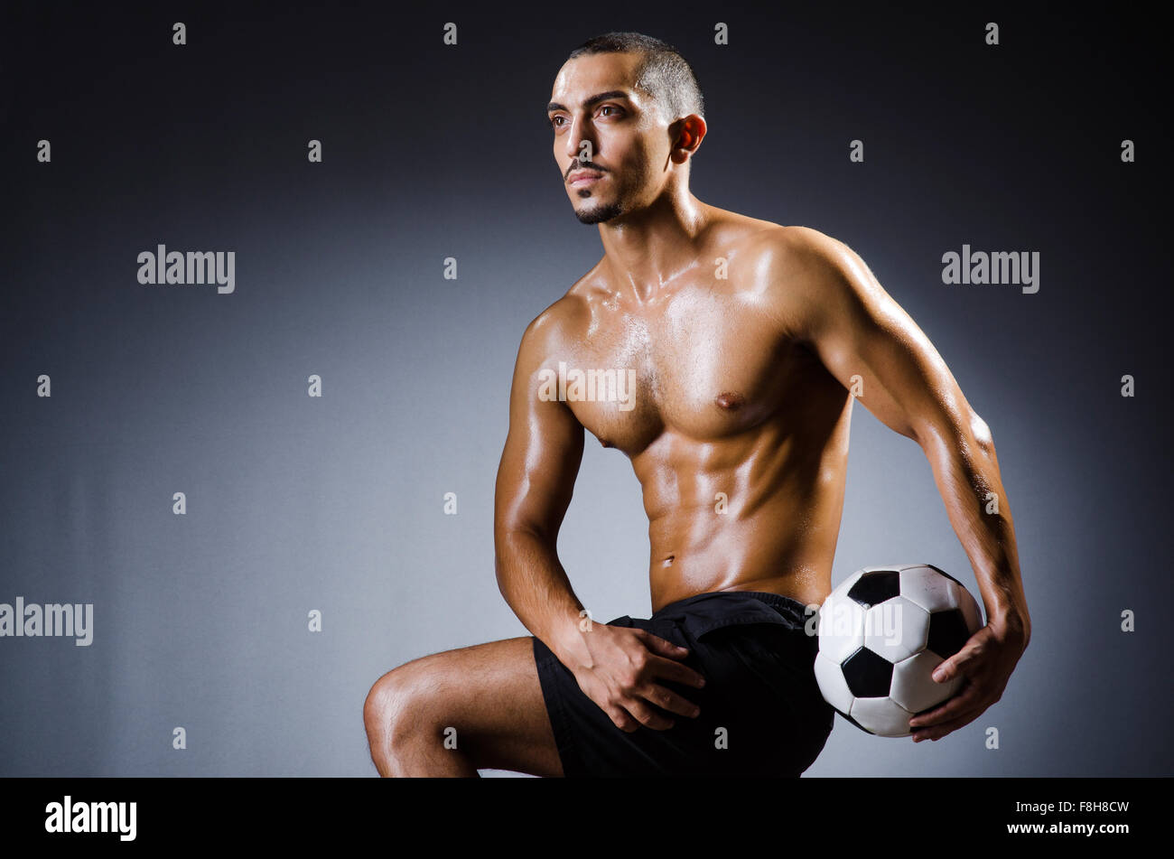 Muscular man with football ball Stock Photo - Alamy