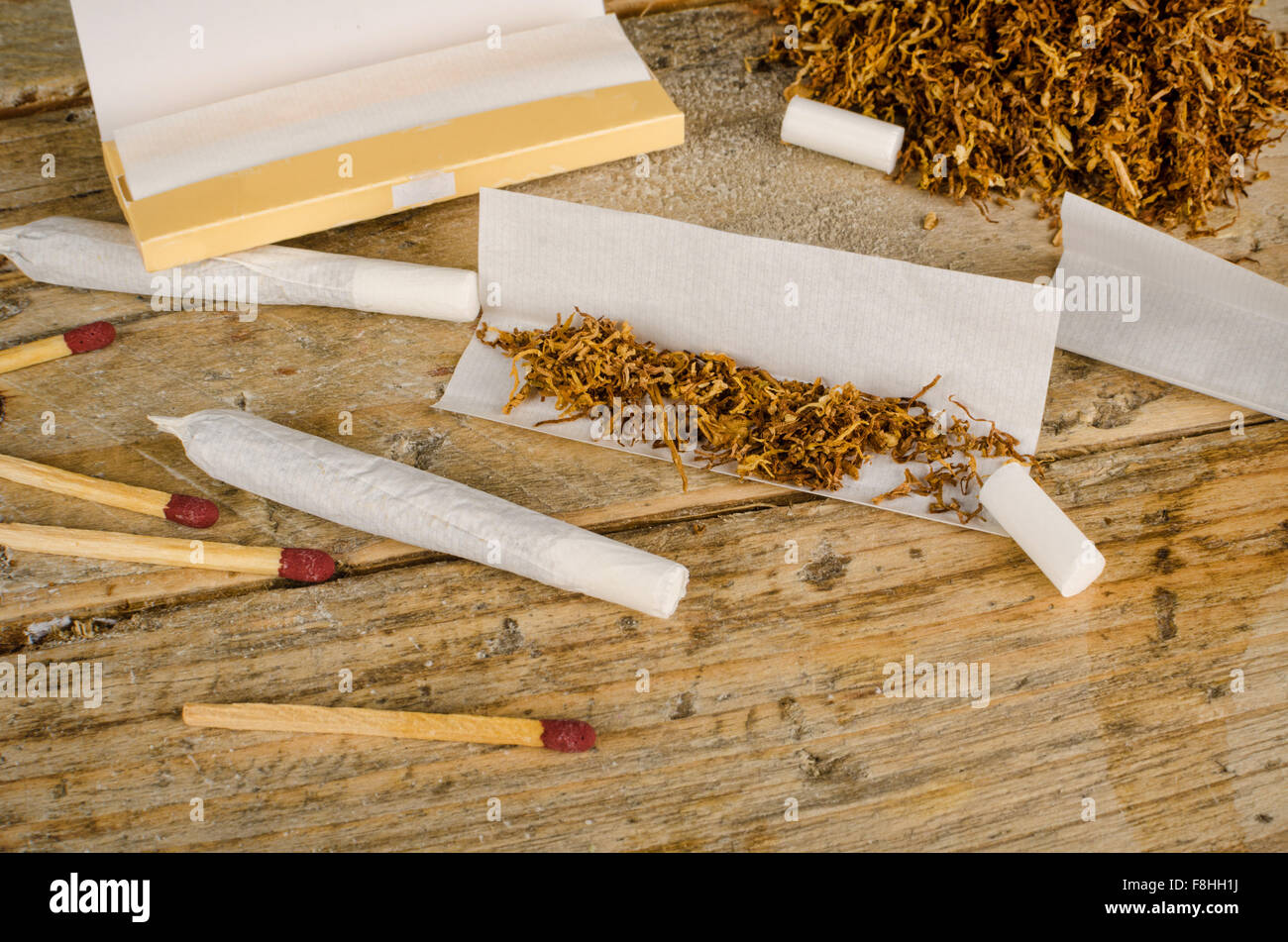 Accesories for rolling and smoking cigarettes on a rustic wooden table ...
