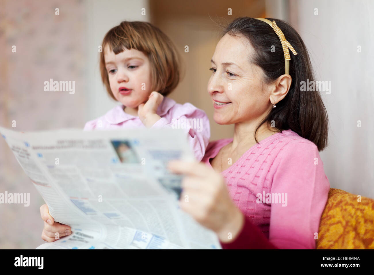 Positive mature woman and child reading newspaper at home Stock Photo - Alamy