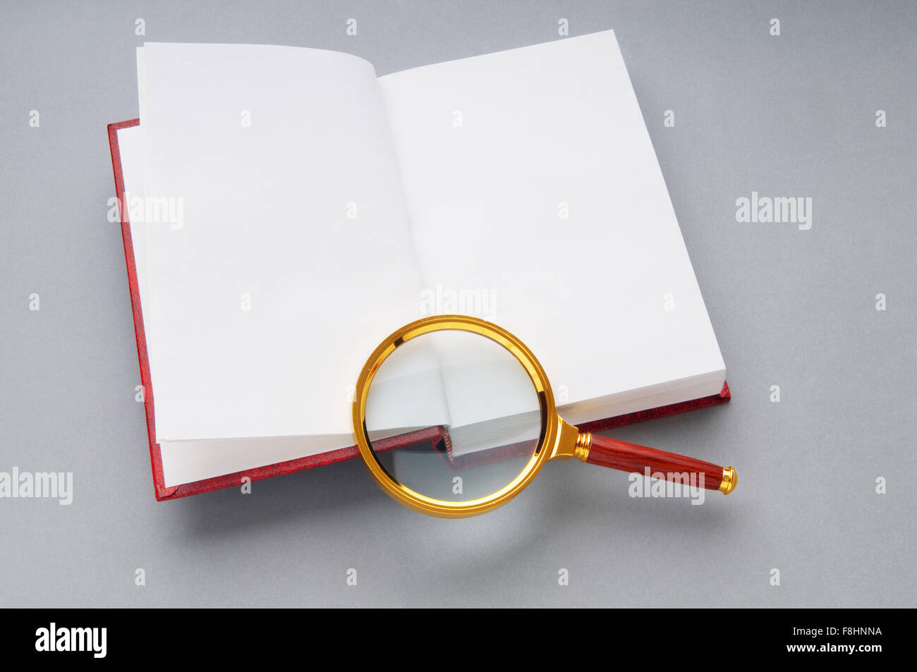 Magnifying glass over the stack of books Stock Photo - Alamy