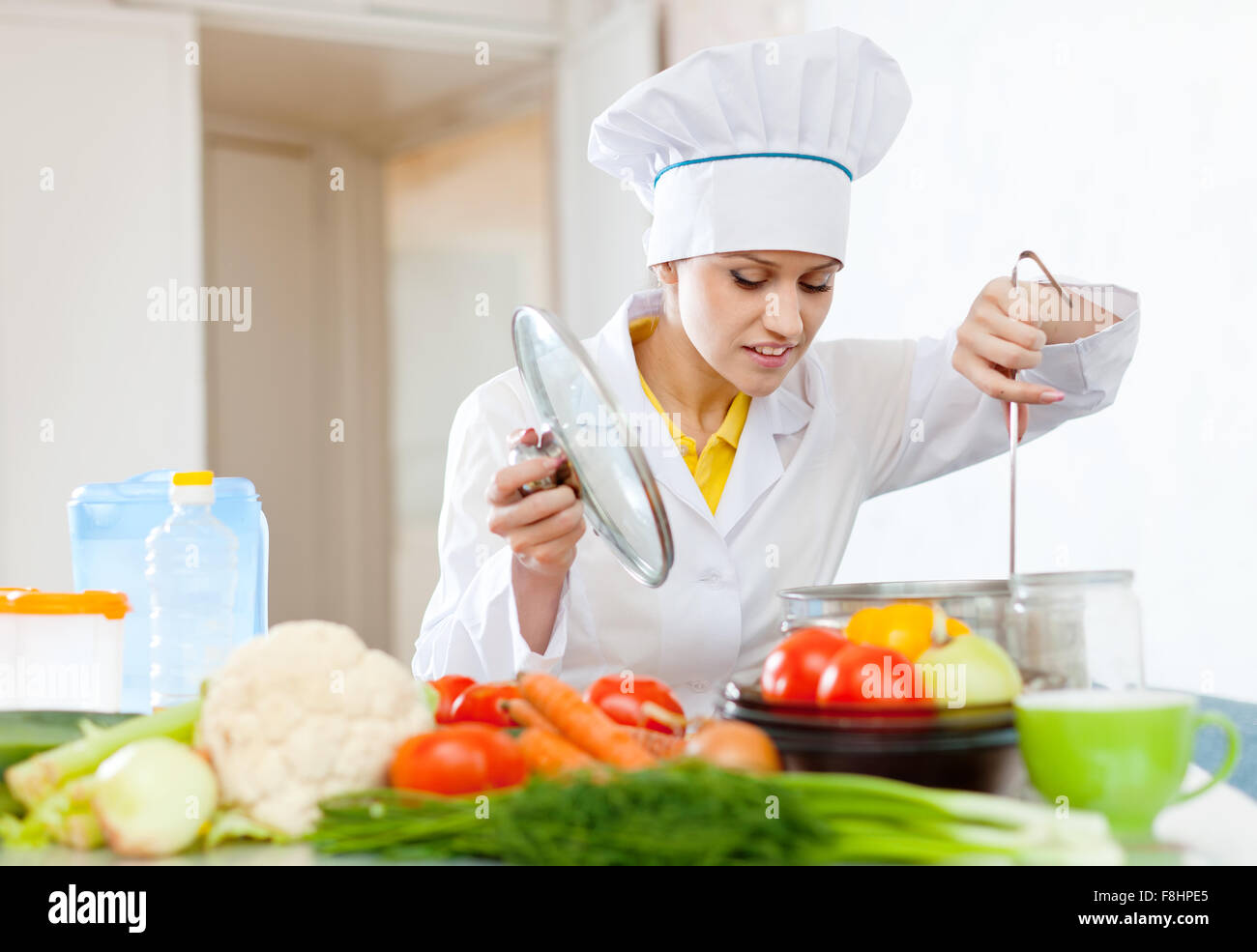 Cook in white hat looks into the pan in kitchen Stock Photo - Alamy