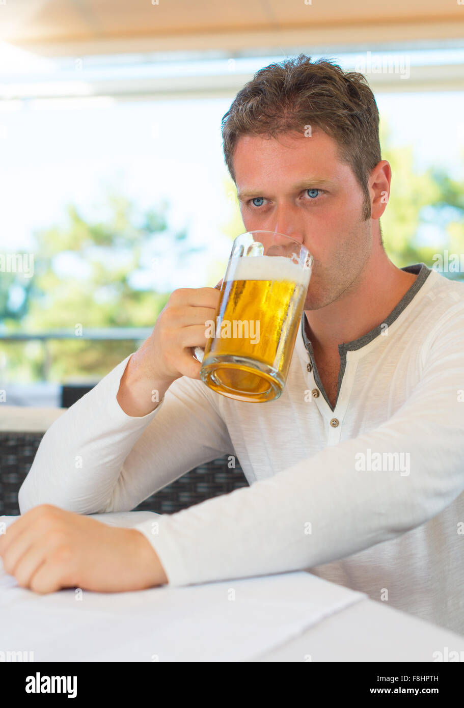 Handsome man drinking beer in summer cafe Stock Photo - Alamy