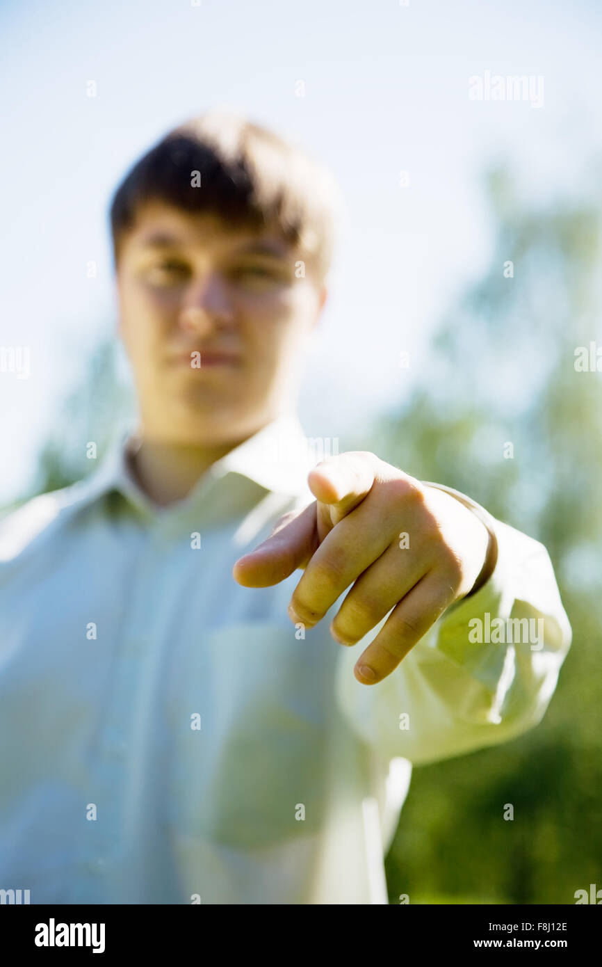 Casual man pointing towards the camera against summer park. Focus on ...