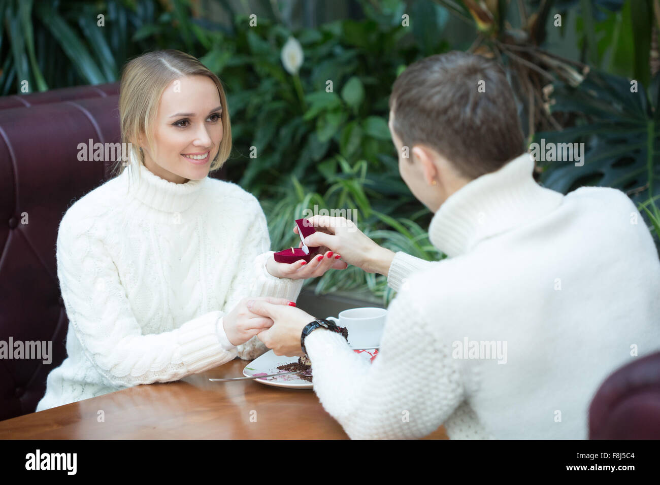 Young man proposing to girlfriend offering engagement ring. sitting in ...