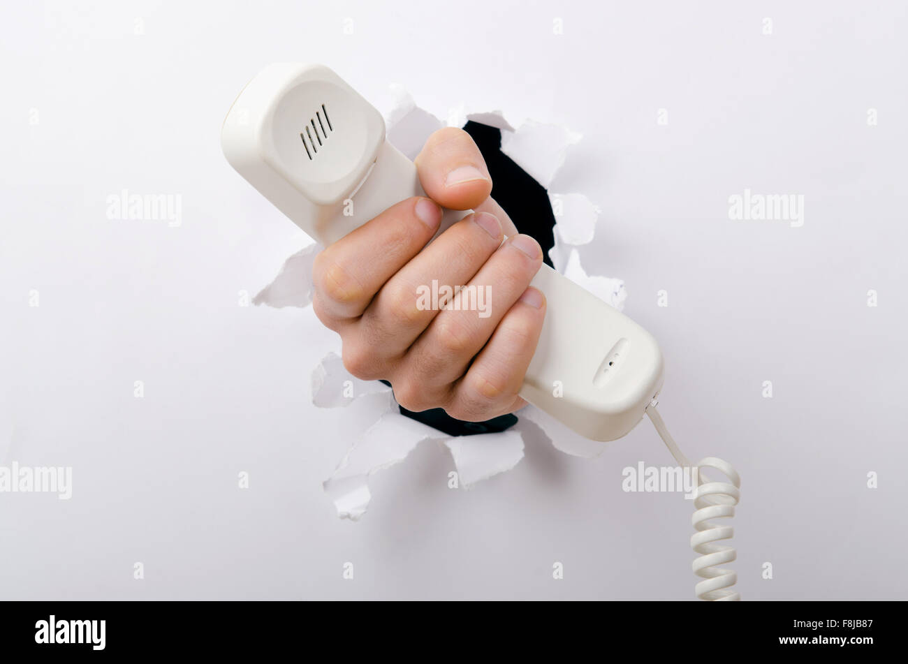 Hand holding phone through hole in paper Stock Photo - Alamy