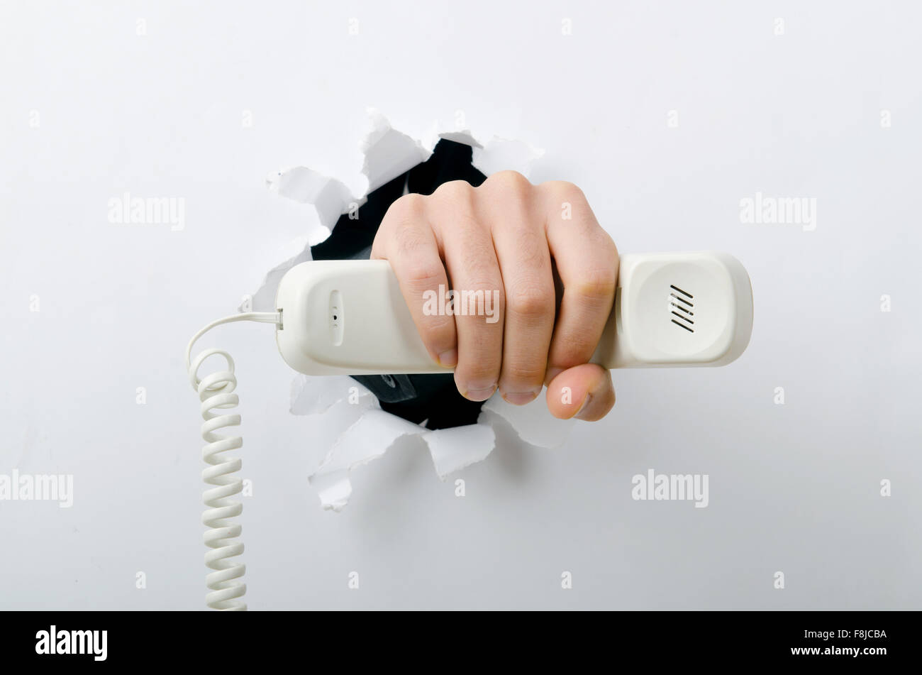 Hand holding phone through hole in paper Stock Photo - Alamy