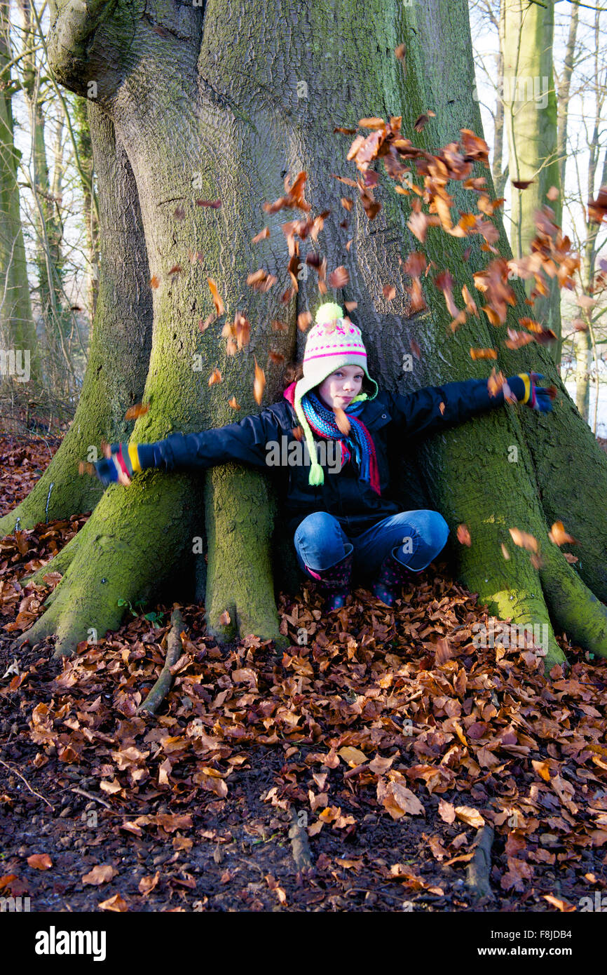 Young girl throwing golden leaves on a bright Autumn day in a forest ...