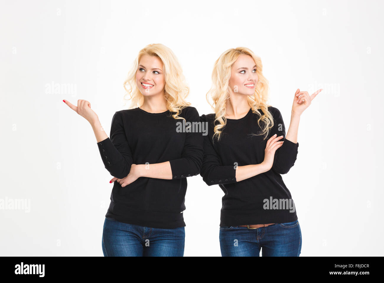 Portrait of a smiling sisters twins pointing fingers away isolated on a ...