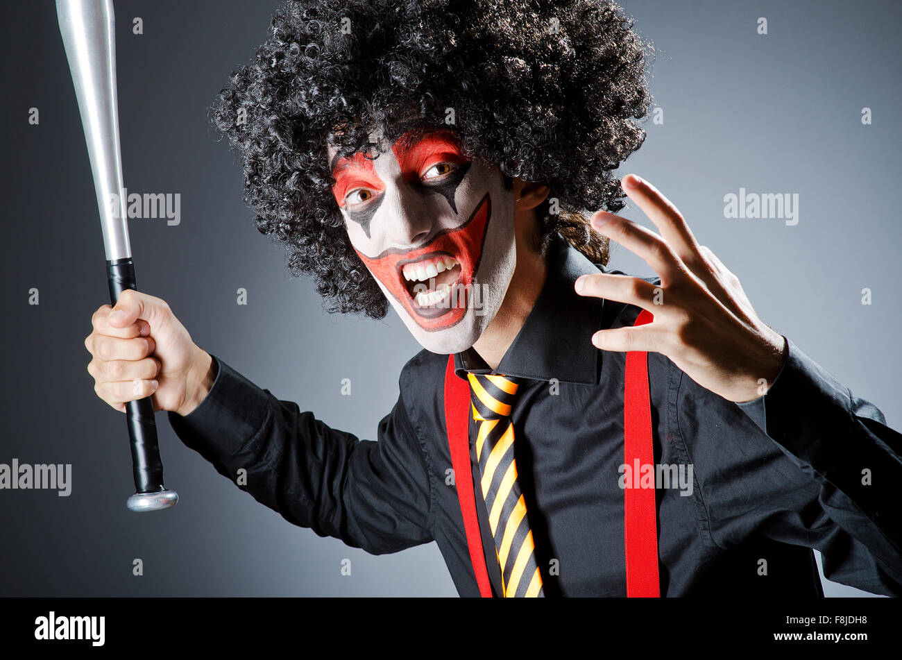 Funny clown with bat in studio Stock Photo - Alamy