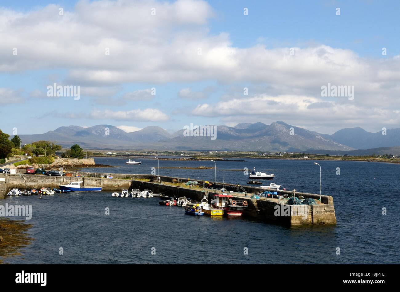 The small Irish Roundstone harbour with the Twelve Bens Mountains in ...