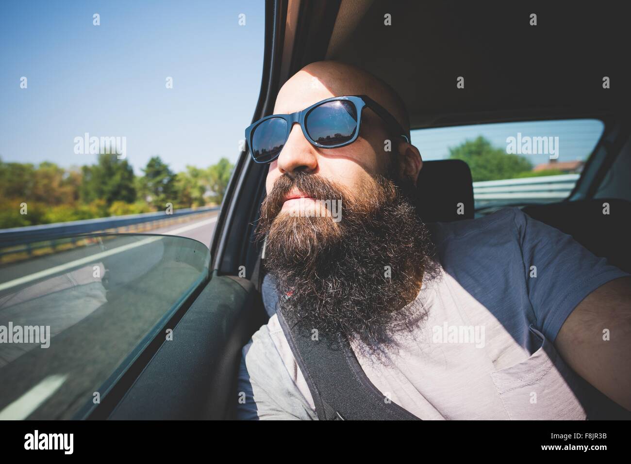 Bearded man looking out of car window on highway, Garda, Italy Stock ...